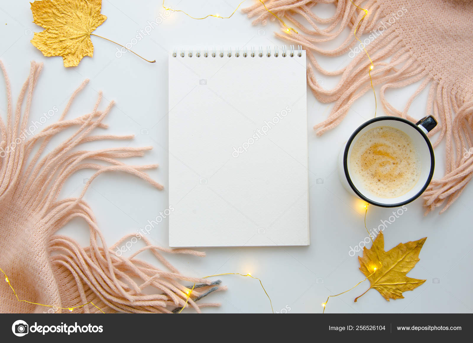 Blank notepad on the white table with knitted pink scarf, coffee mug ...