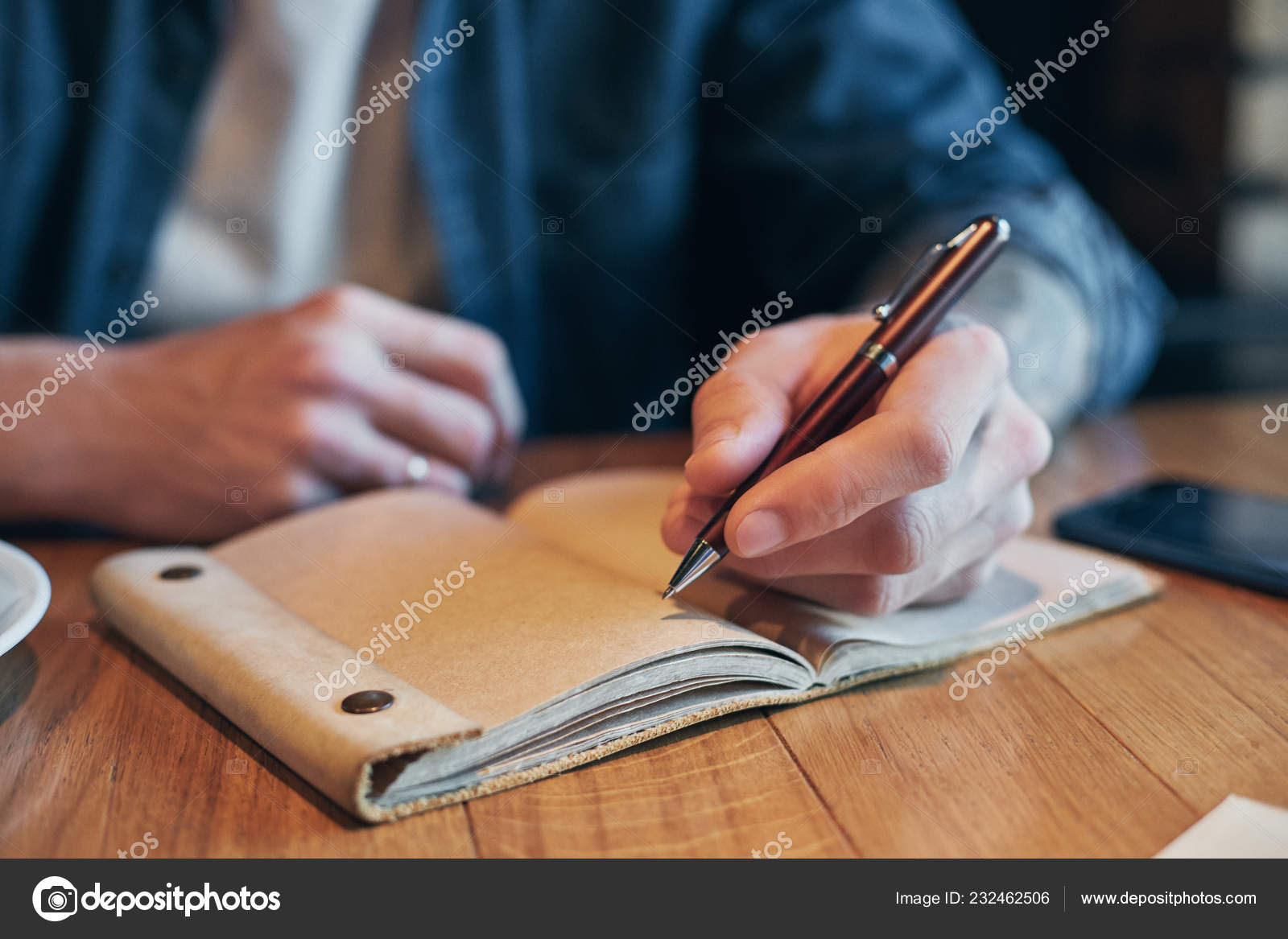 Man hand with pen writing on notebook on a wooden table. Close-up Stock ...