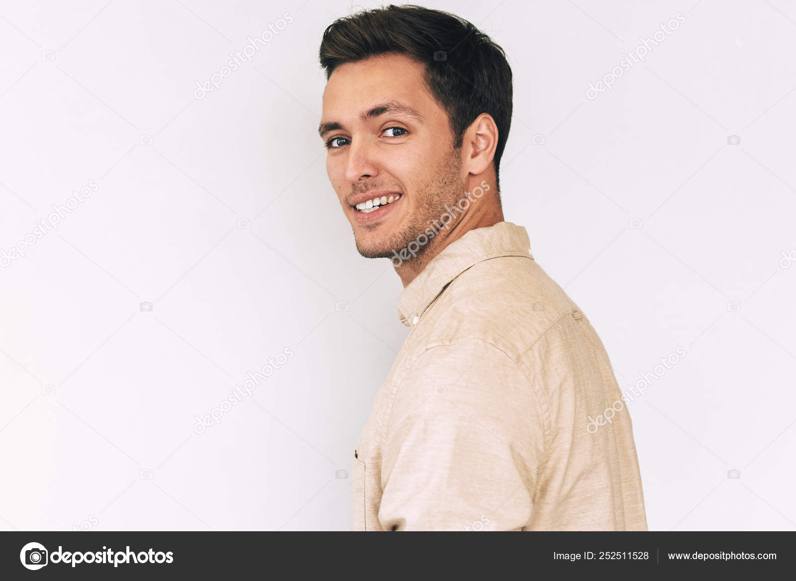 Rear view shot of handsome young man smiling and wearing casual beige ...