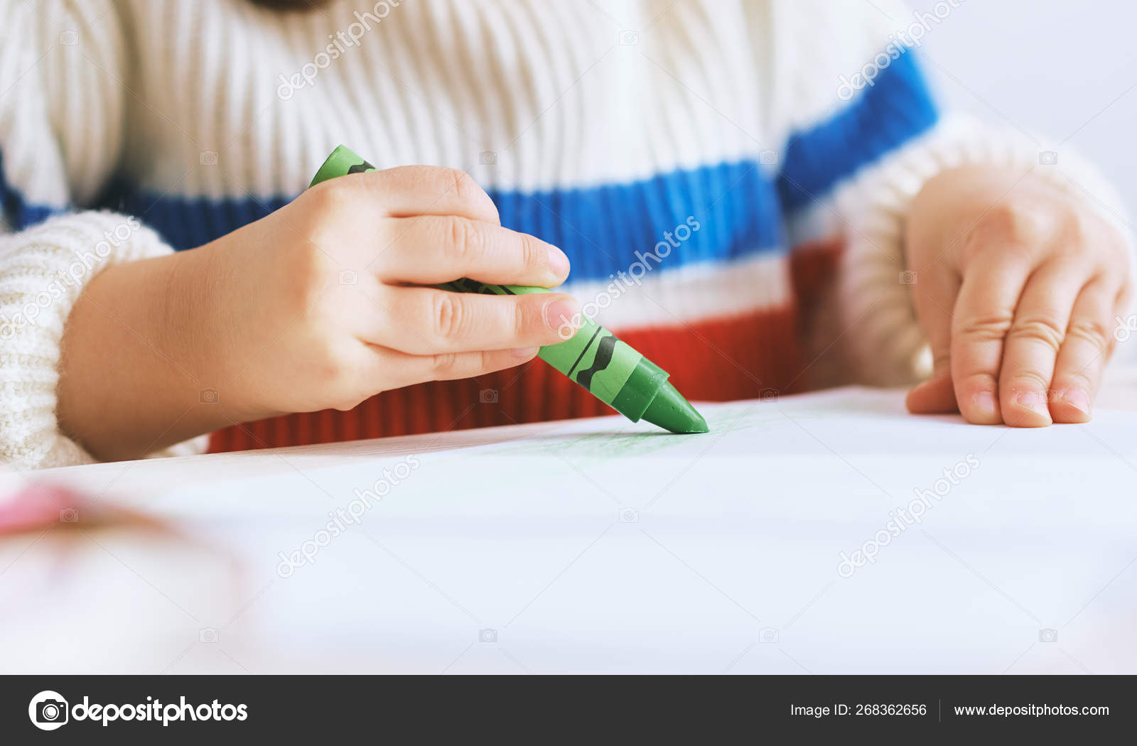 Image of child's hands drawing on white paper with colorful pencil at ...
