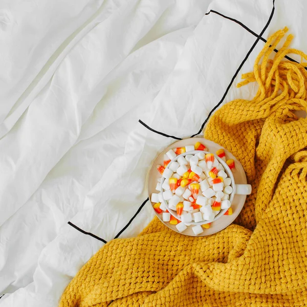 Coffee with marshmallow and candy corn on bed with warm plaid. Autumn ...