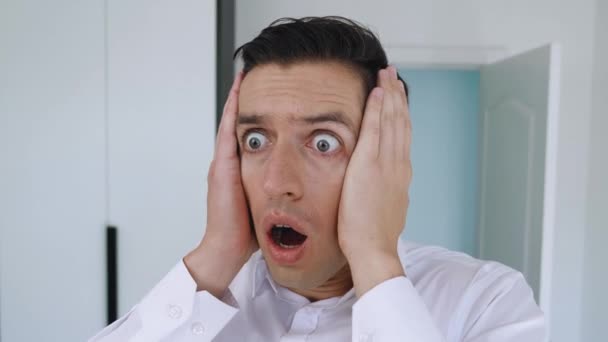 Scared businessman looks into camera with startle at face clutches his ...