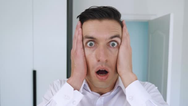 Scared businessman looks into camera with startle at face clutches his ...