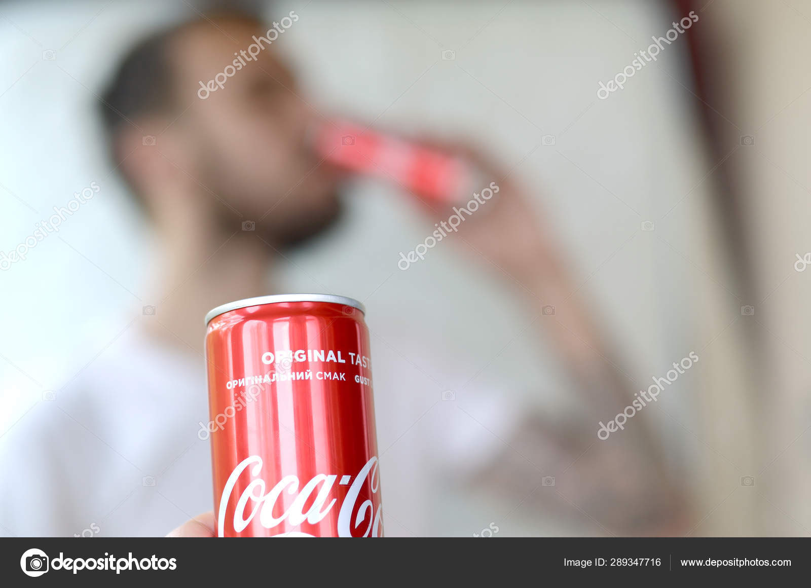 Caucasian man drinks Coca-Cola drink in garage interior and male hand ...
