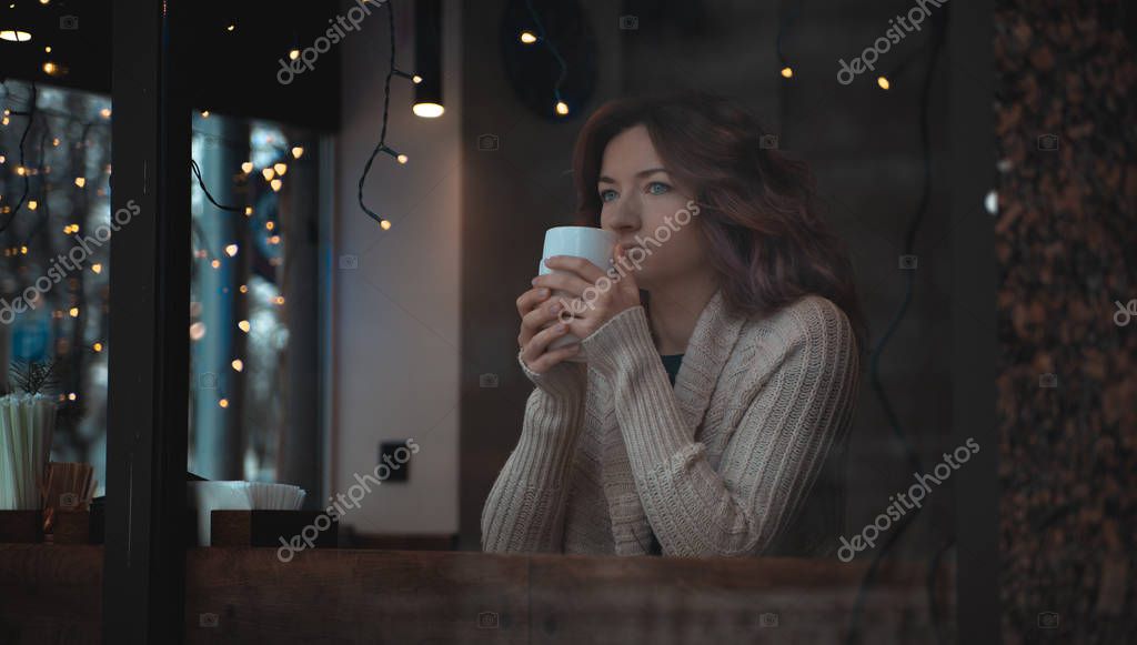chica en un su ter blanco est sentado junto a la ventana decorada con festones en una cafeter a ...