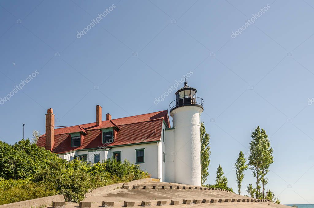 Faro Point Betsie con su techo rojo y edificio blanco. La luna está ...