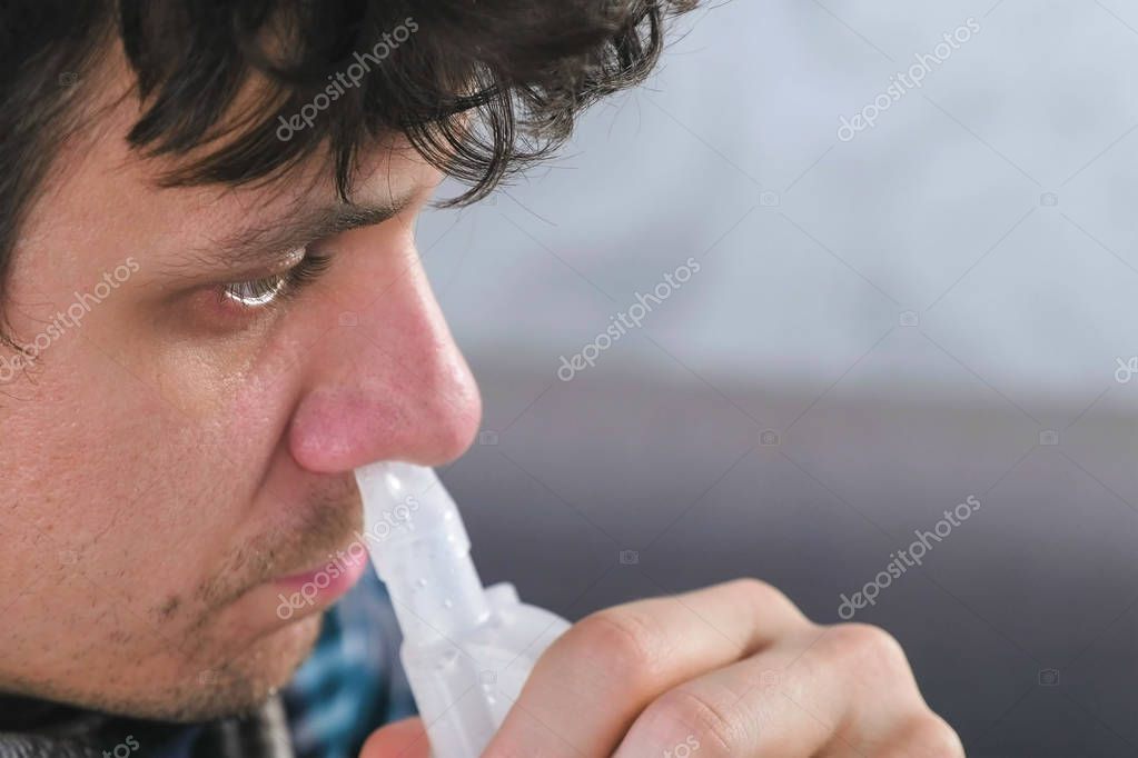 Hombre enfermo inhalando a través de la boquilla del inhalador para la ...