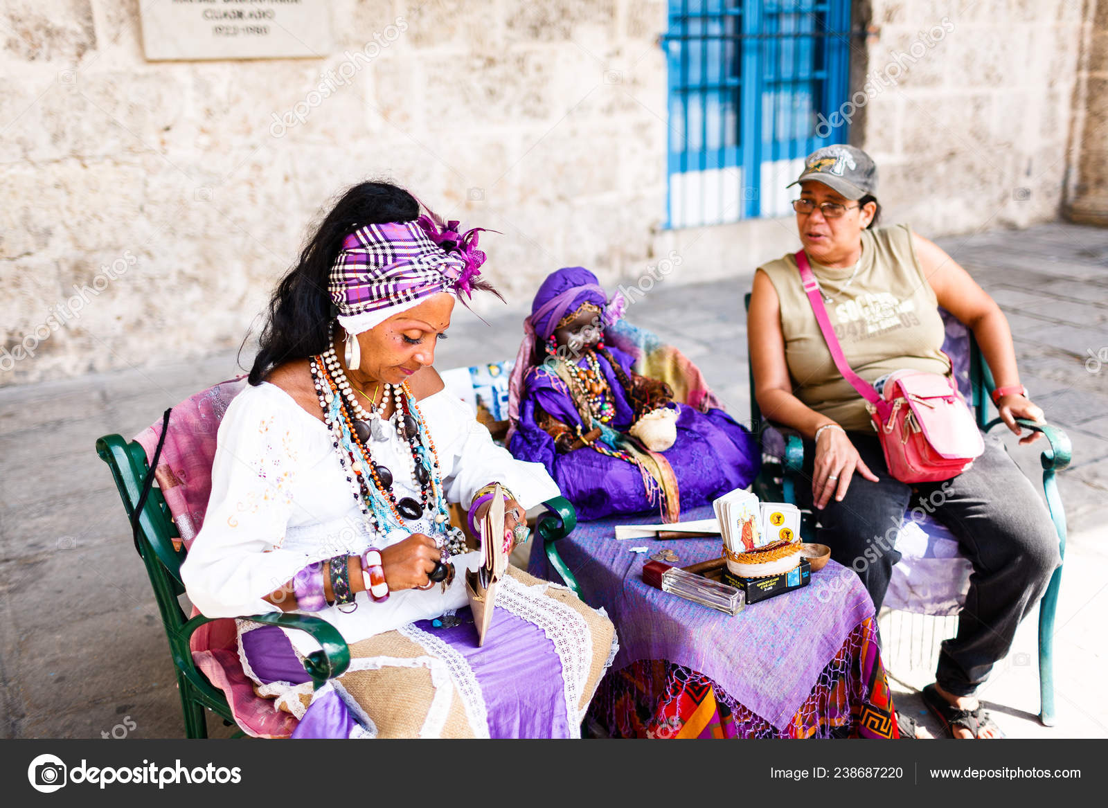 Dark-skinned Cuban in white costume tells fortunes to tourists in ...