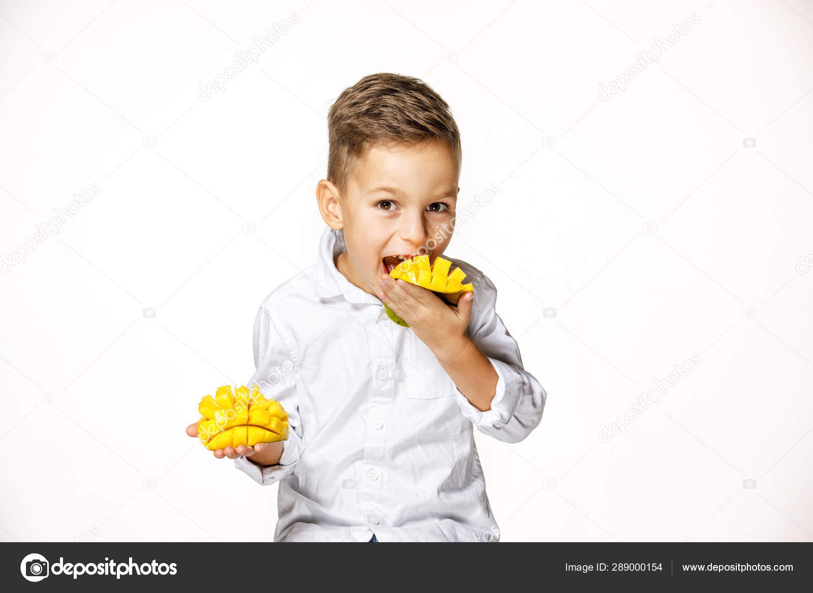 Handsome boy in a white shirt is eating a mango — Stock Photo ...