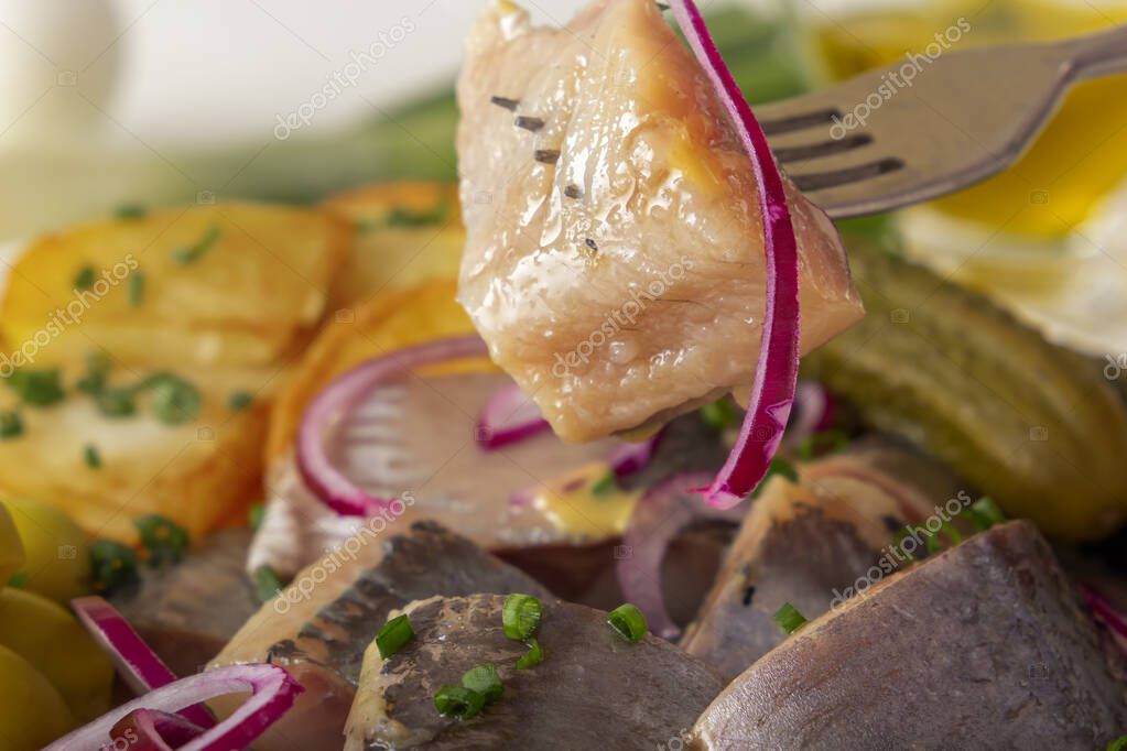 Tenedor pincha un pedazo de arenque en escabeche de un plato de ...