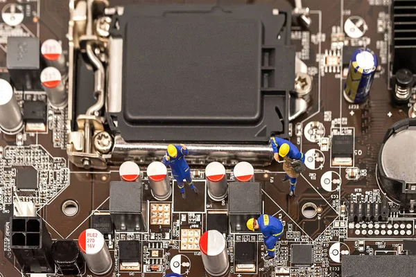 Miniature Group Engineers inspecting computer processor with chip and ...
