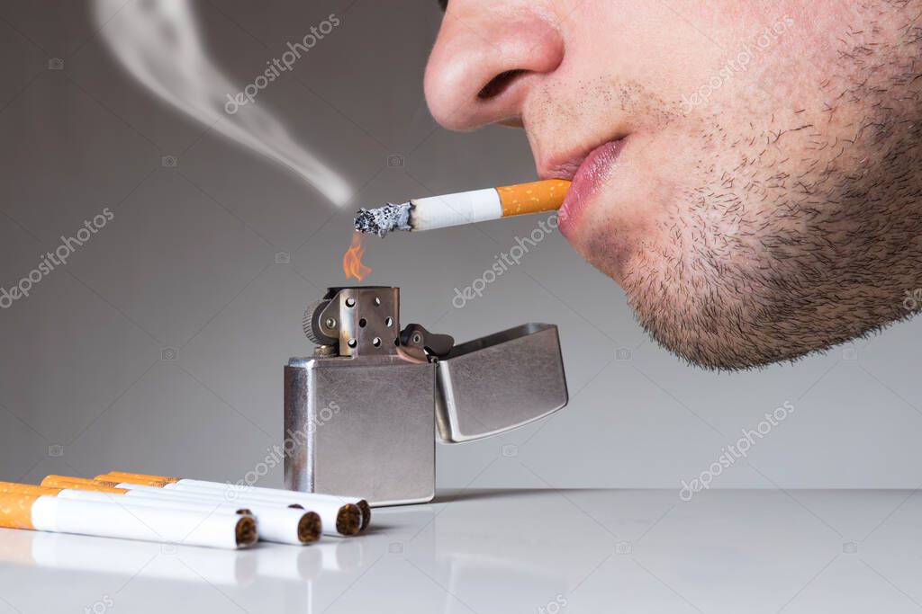 Hombre joven fumando cigarrillo con clásico viejo encendedor rayado ...