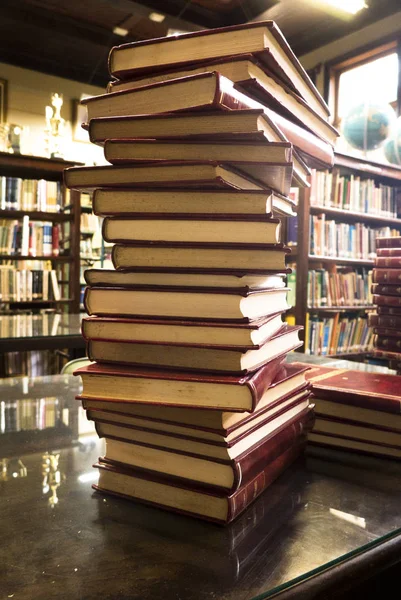 Book stack on wood desk and blurred bookshelf in the vintage library ...