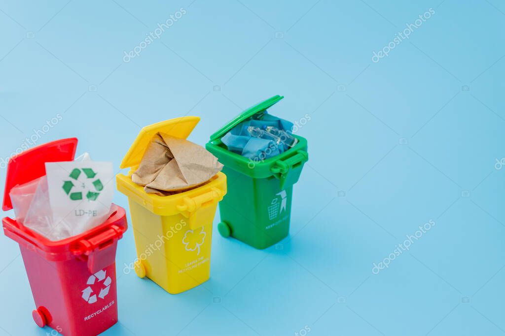 Papeleras de reciclaje amarillas, verdes y rojas con símbolo de reciclaje sobre fondo azul ...