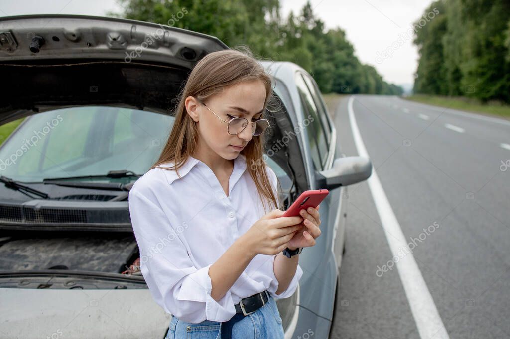 Mujer joven de pie cerca de coche roto con capucha estallado tener ...