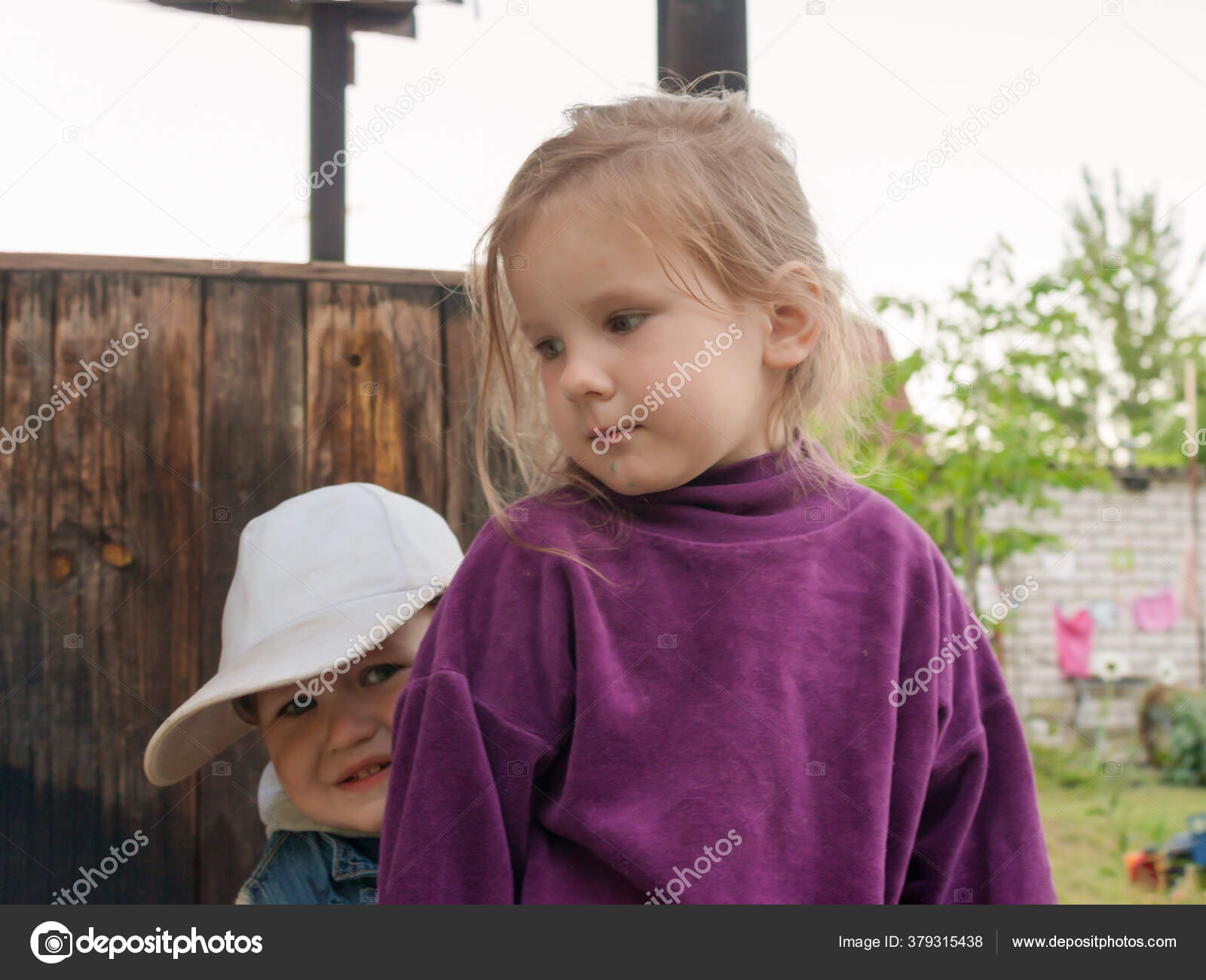 Little boy is upset and scared. The younger brother is hiding behind ...