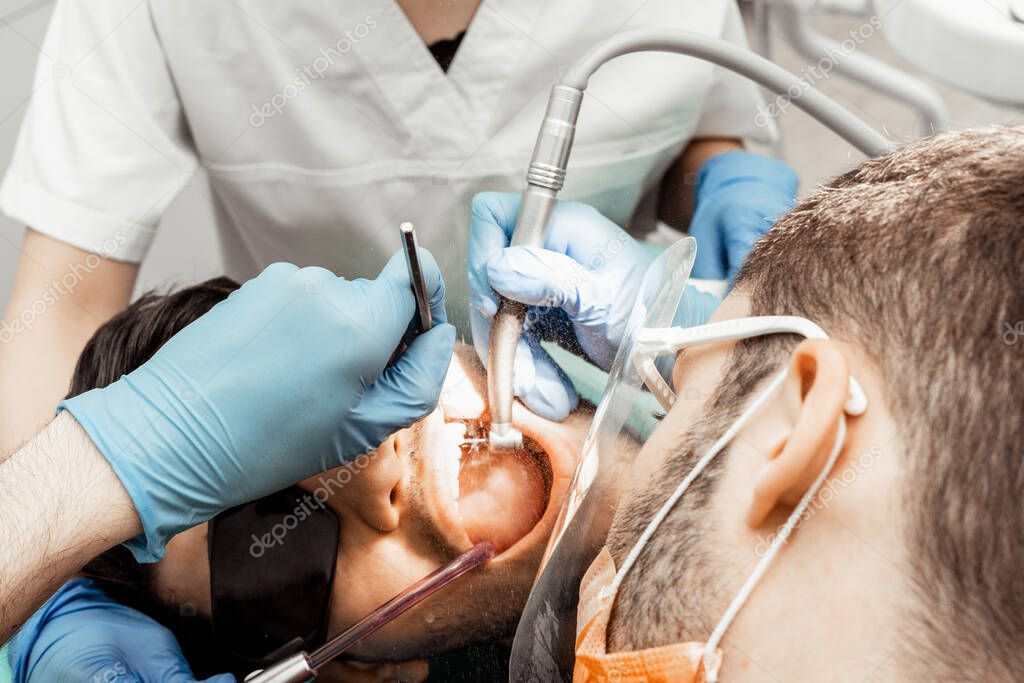 Dos dentistas tratan a un paciente. Uniforme profesional y equipo de dentista. Cuidado de la ...