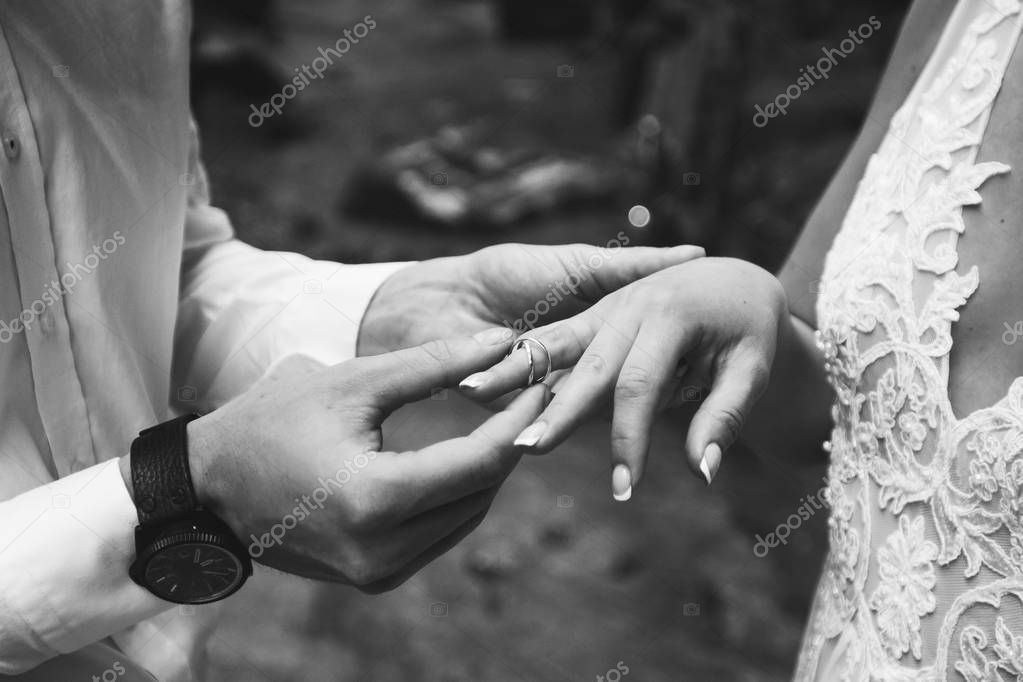 foto monocromática del novio poniendo anillo en la mano de las novias ...