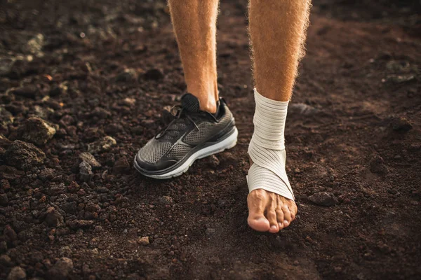 Man's ankle in compression bandage. Leg injury while trail runni ...