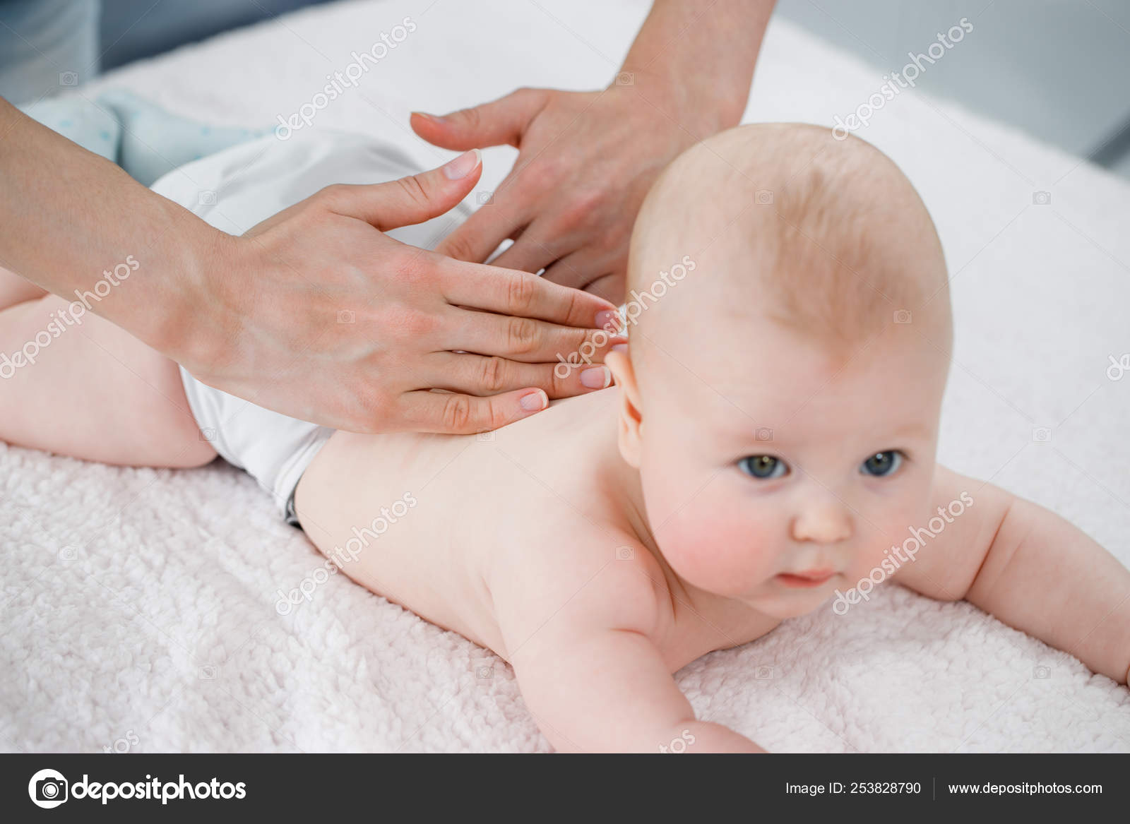 Mother's hands massage the muscles of the back of her baby. Stock Photo ...