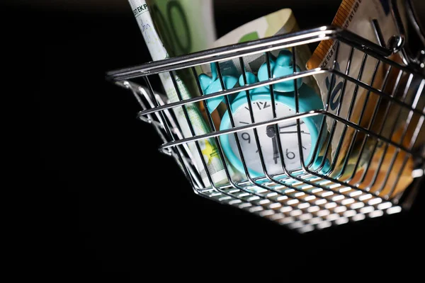 Small shopping basket full of euro banknote, with small retro alarm ...