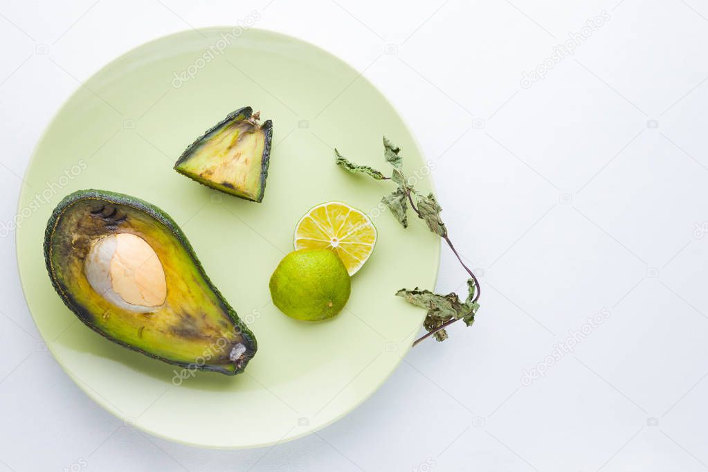 Comida fea sobre fondo blanco. Aguacate podrido en plato verde. Cal ...