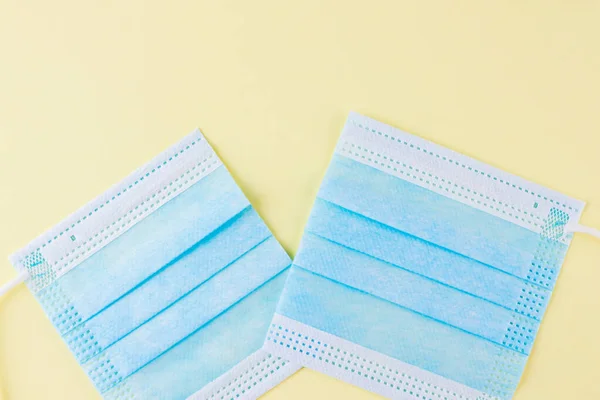 Two parts of cut surgical mask on a yellow background. Covid-19 ...