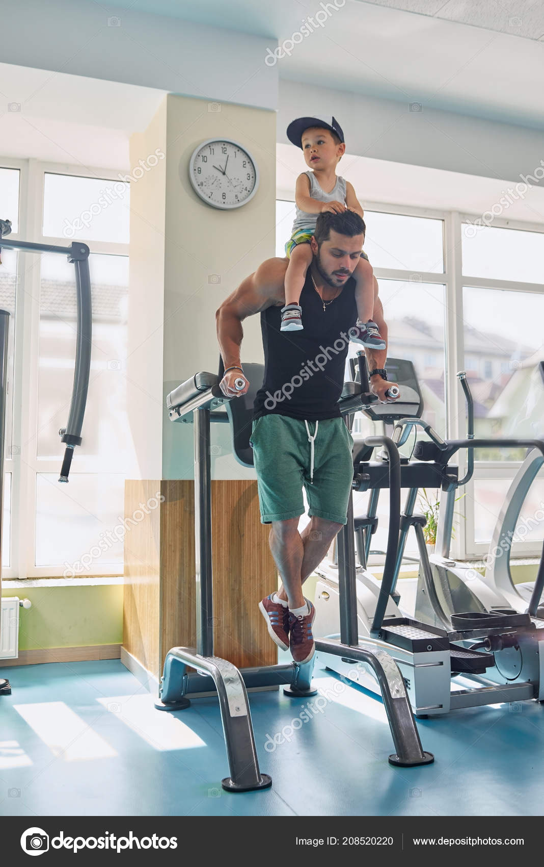 Front view of sportsman training on simulator keeping little son on ...