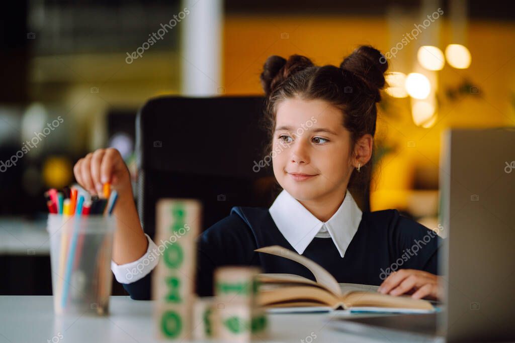 Una colegiala sonriente con uniforme escolar sentada a la mesa con ...