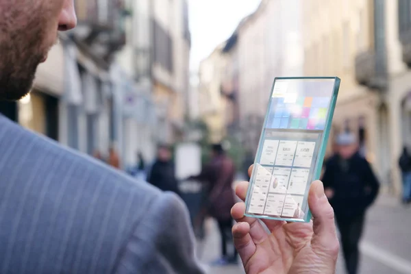 The hand of a man in suits, uses a futuristic glass phone with the ...