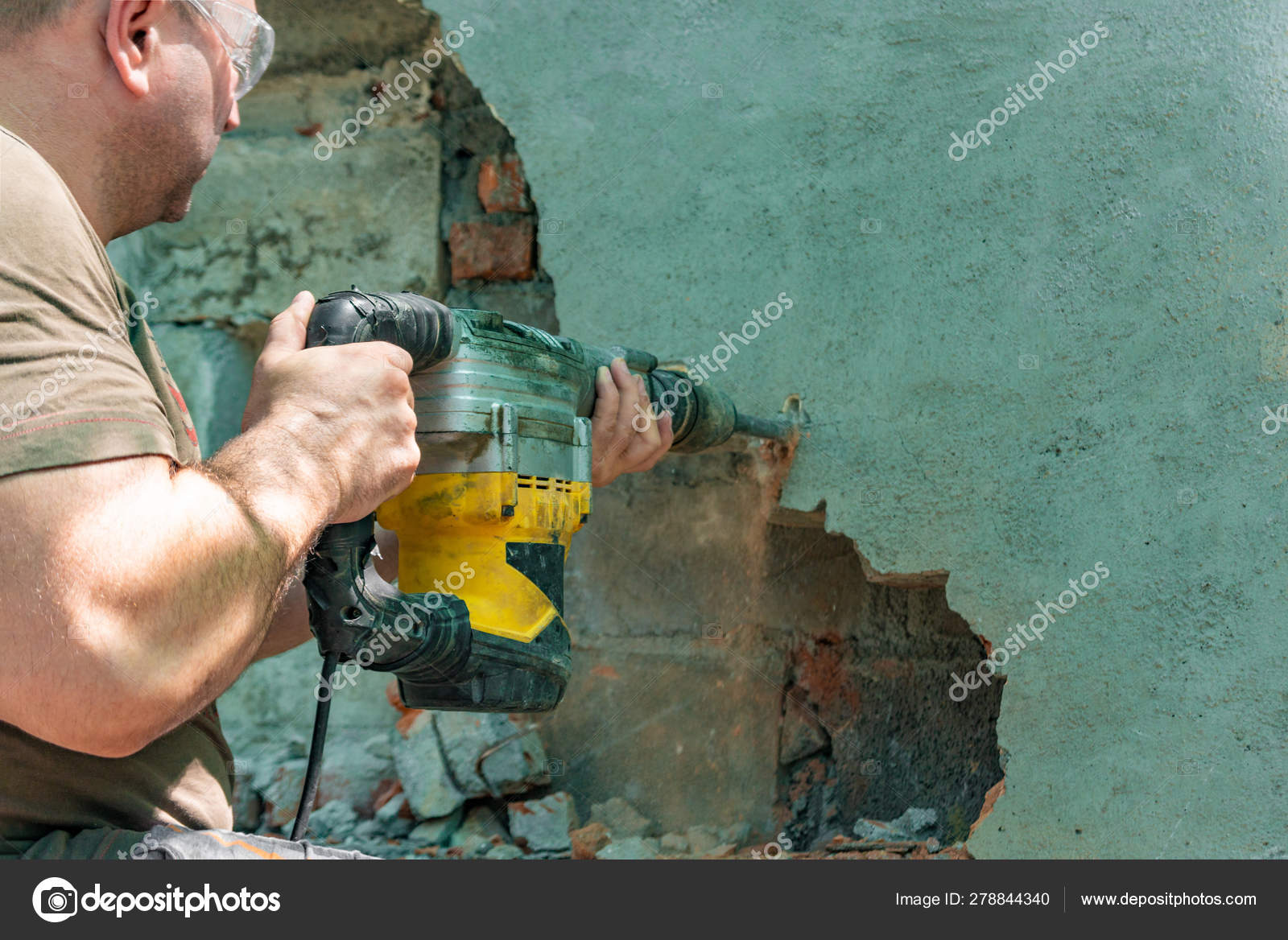 Dismantling walls and openings with an electric jackhammer. The worker ...