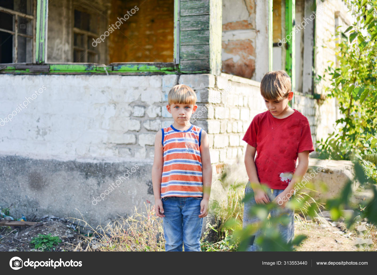 Two brothers are standing near a burned-out house, who lost thei Stock ...