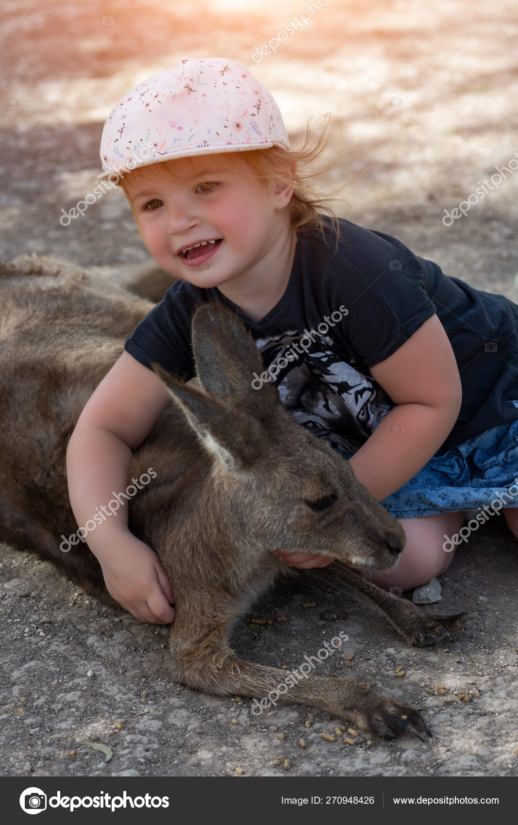 Linda chica joven y canguro en el zoológico. Niña de 1-2 años alimenta ...