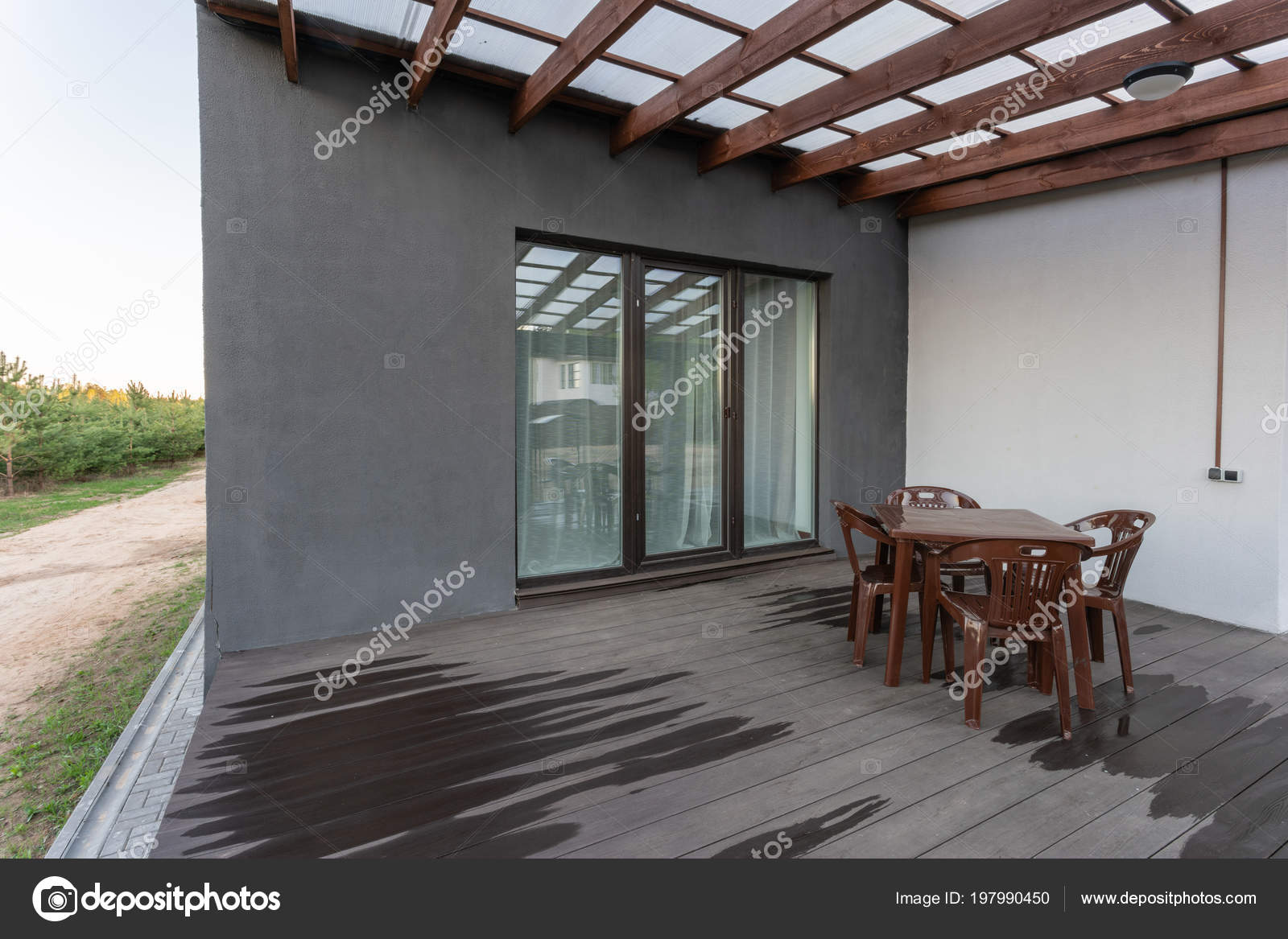 Side view of an open veranda in front of a modern forest cottage. Pine ...