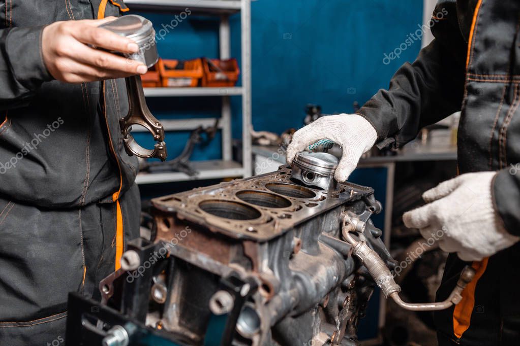 Dos mec nicos sosteniendo un nuevo pist n para el motor, revisi n.. Motor en un soporte de ...