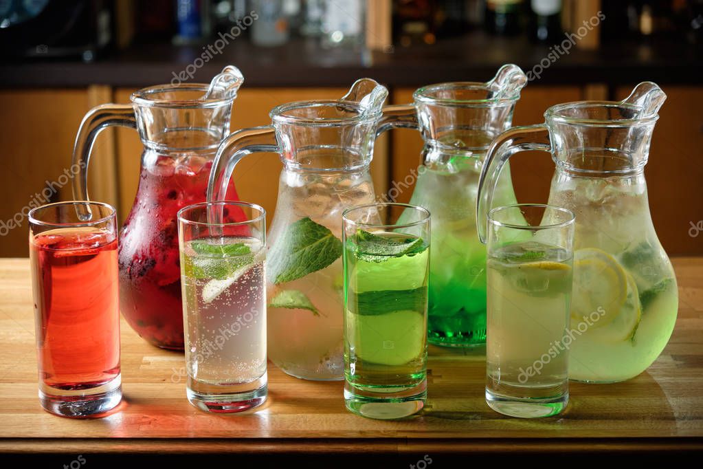 Diferentes refrescos en jarras transparentes sobre un fondo de madera ...