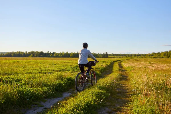A young woman rides a bicycle on a field road. Summer sunny day - Stock ...