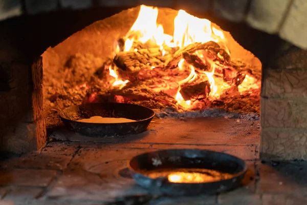 Cooking in the fireplace. Pancakes in a pan are fried on a fire in the ...