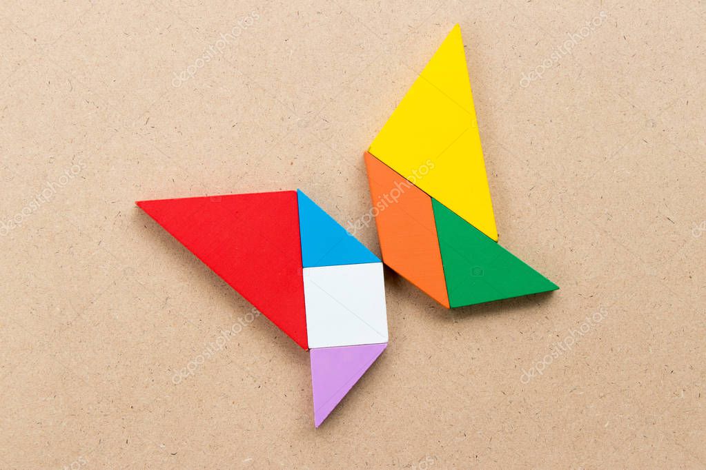 Rompecabezas tangram color en forma de mariposa sobre fondo de madera 2024