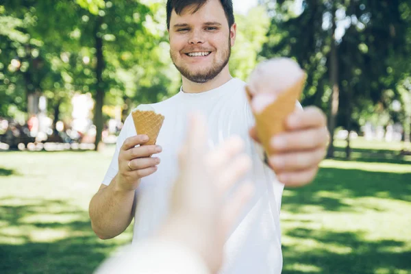 man giving ice cream in hot sunny day in city park. first person point ...