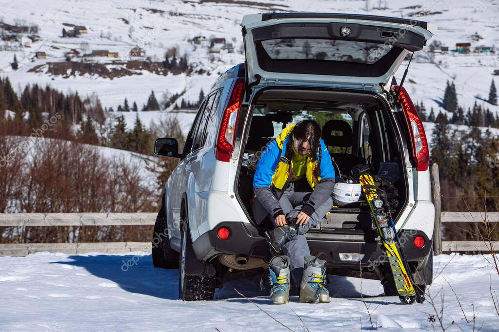 mujer cambiando botas para esquiar sentado en el maletero del coche ...