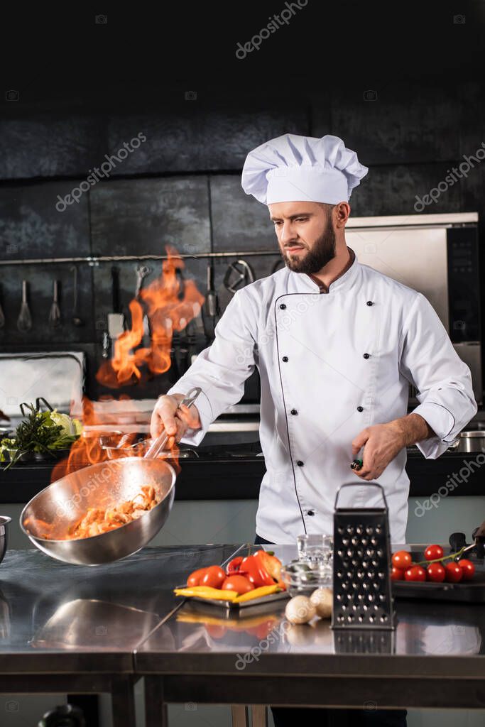Chef preparar la comida con fuego en el restaurante de cocina. Chef con ...