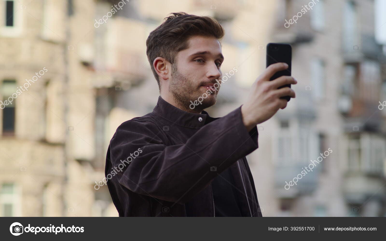 Smiling guy having video call outdoors. Excited man looking phone ...