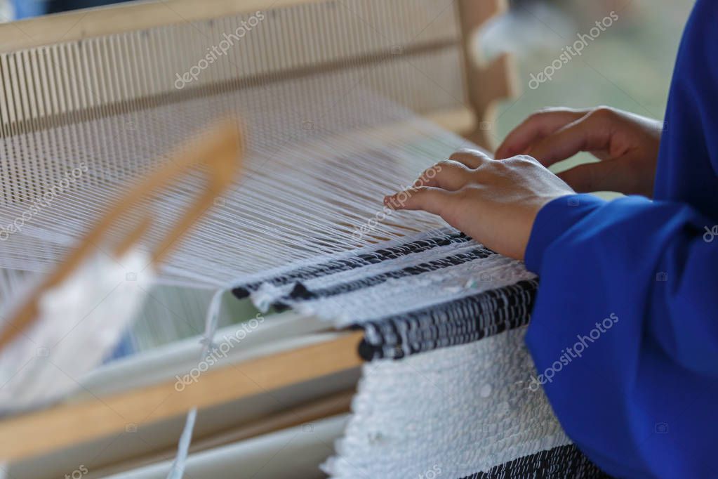 Mujer joven teje un paño blanco en un telar de madera de la mano. Arte ...