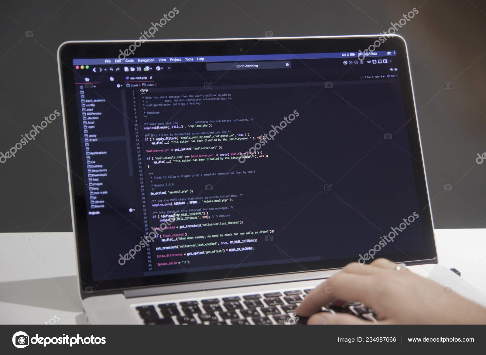 Male programmer working on laptop computer at white desk in office ...