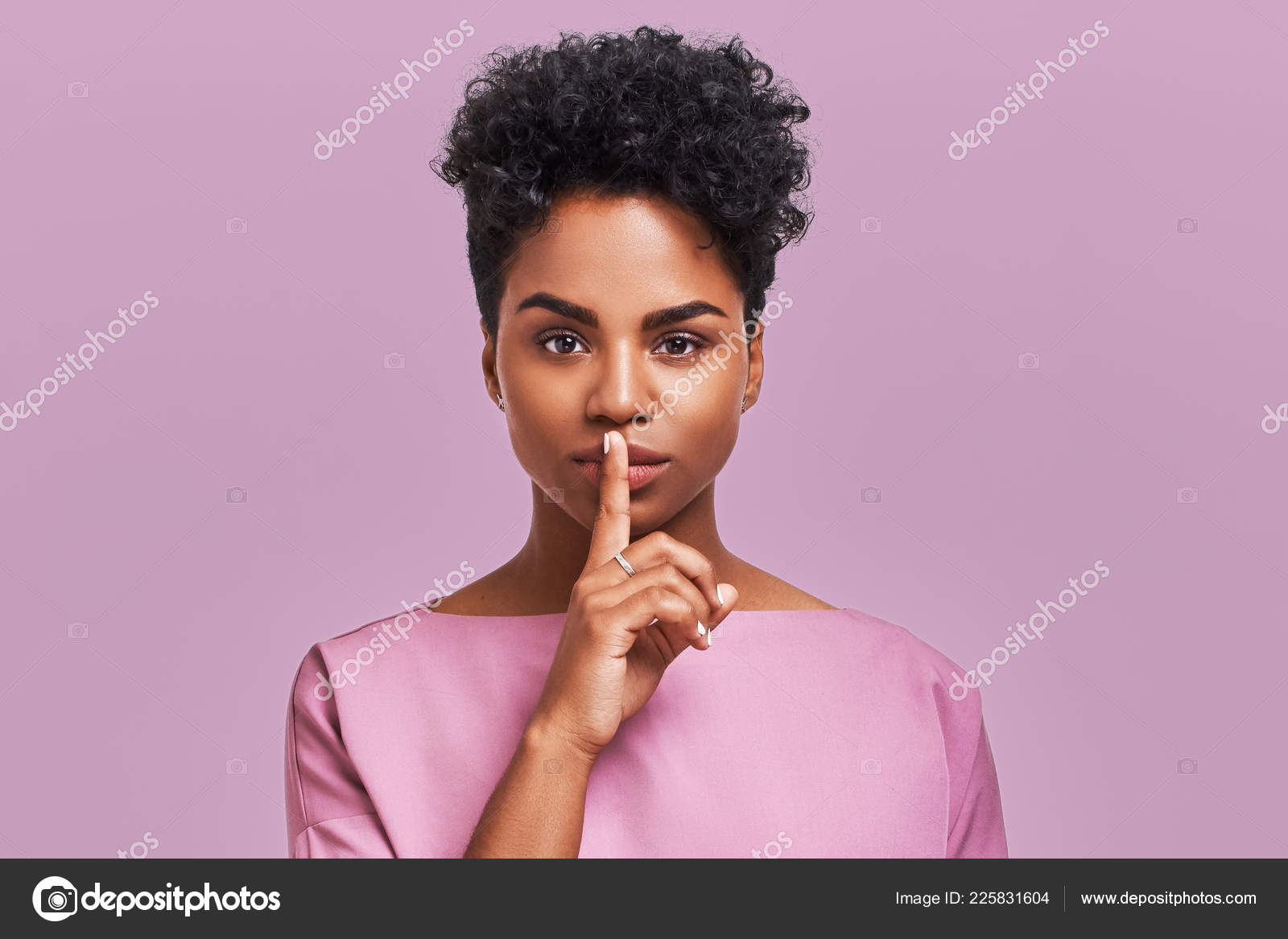 Terrific dark skinned girl keeps fore finger on lips, has mysterious ...