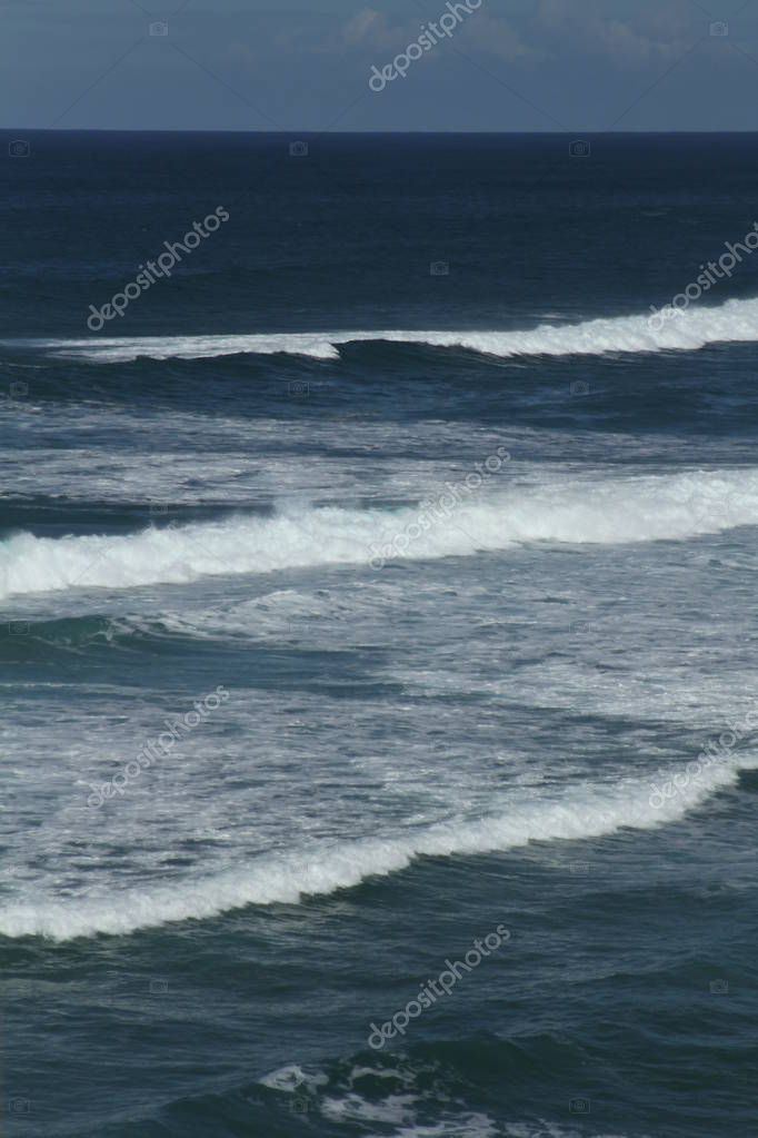 Olas rompiendo en la costa, spray, agua blanca y luz reflejada en la ...