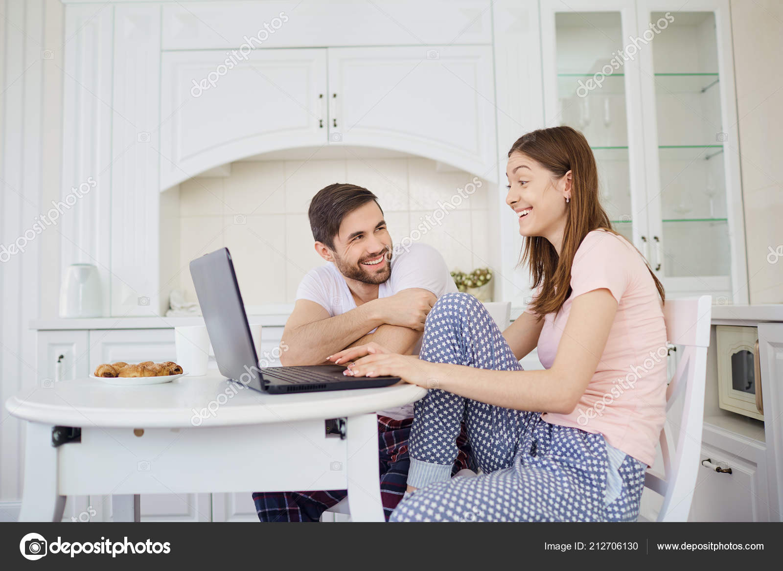 A young couple is having breakfast at the table, working with a Stock ...
