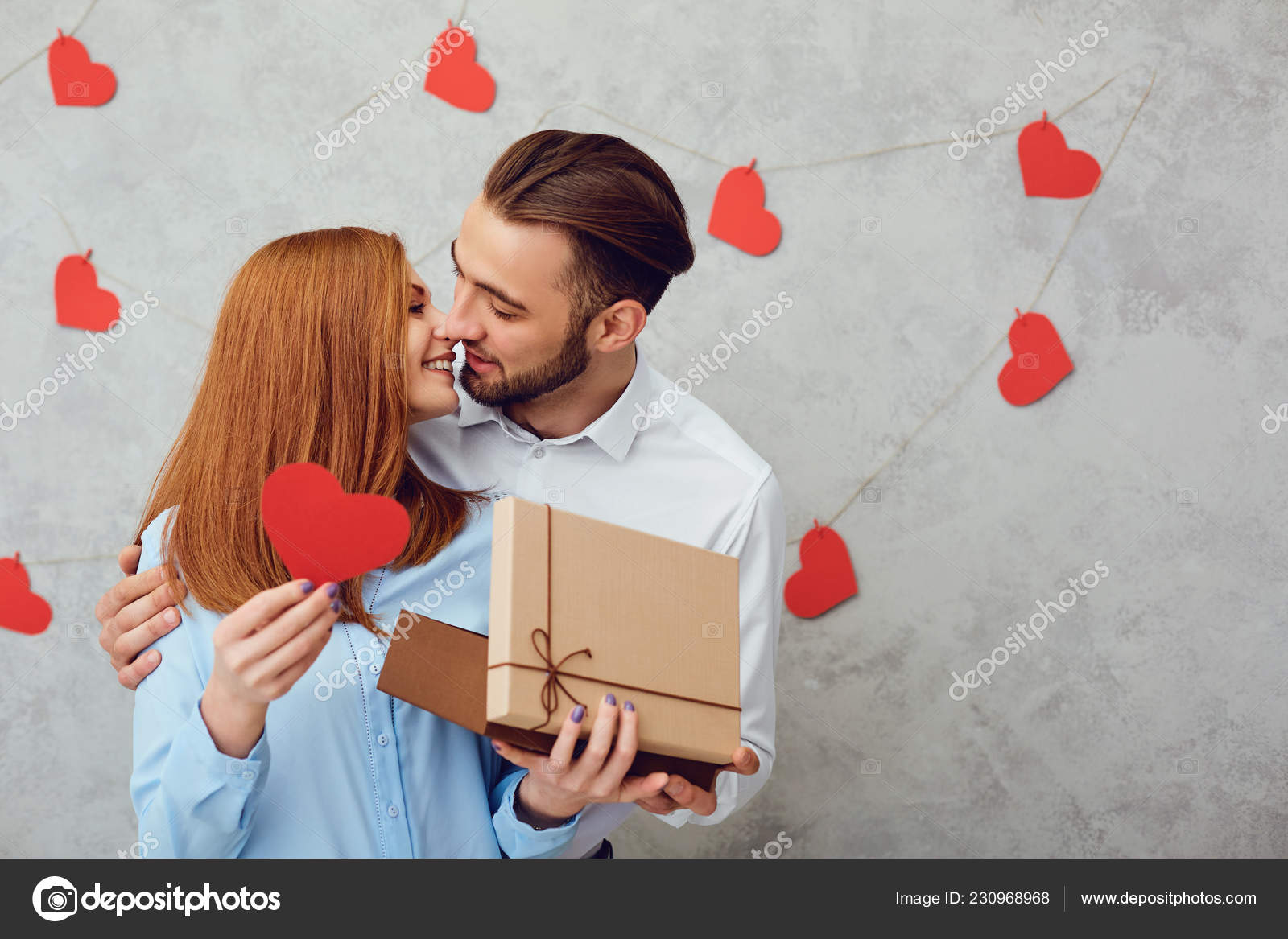 A young couple gives a gift on a gray background. Stock Photo by ...
