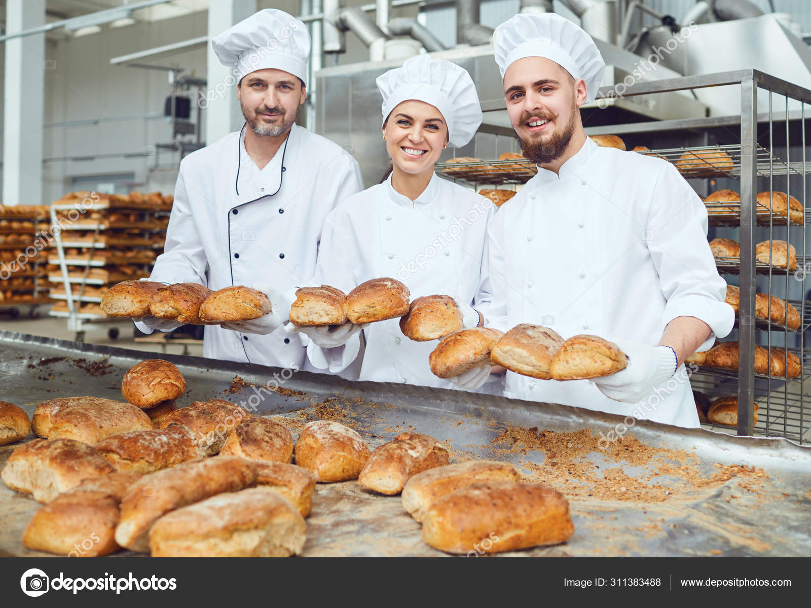 Panaderos sonriendo sosteniendo pan fresco en sus manos en una ...